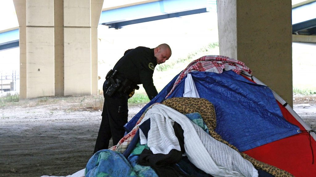 Police officers work to help occupants of homeless encampments ...